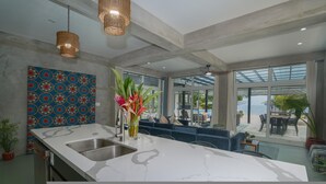 Cozinha moderna com uma ilha grande, área de jantar com vista e sala de estar com sofá e cadeiras.