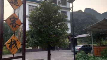 Um edifício com arquitetura tradicional, uma árvore em primeiro plano e um carro estacionado ao fundo.