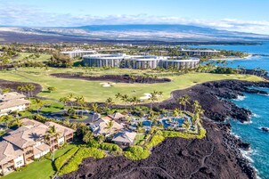 Um resort com vários edifícios, campo de golfe e uma orla costeira.