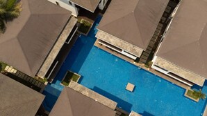 Vista aérea de uma área residencial com uma piscina central cercada por casas.