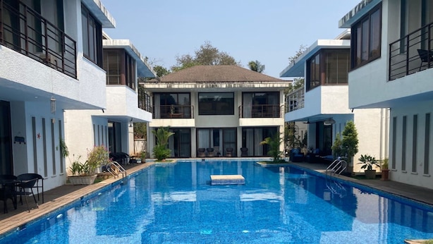 Piscina com deck revestido, cercada por edifícios modernos com varandas e janelas amplas.
