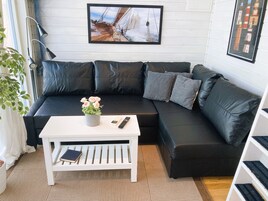 Uma sala de estar moderna com um sofá de couro preto, uma mesa de centro branca e um quadro de um veleiro na parede.