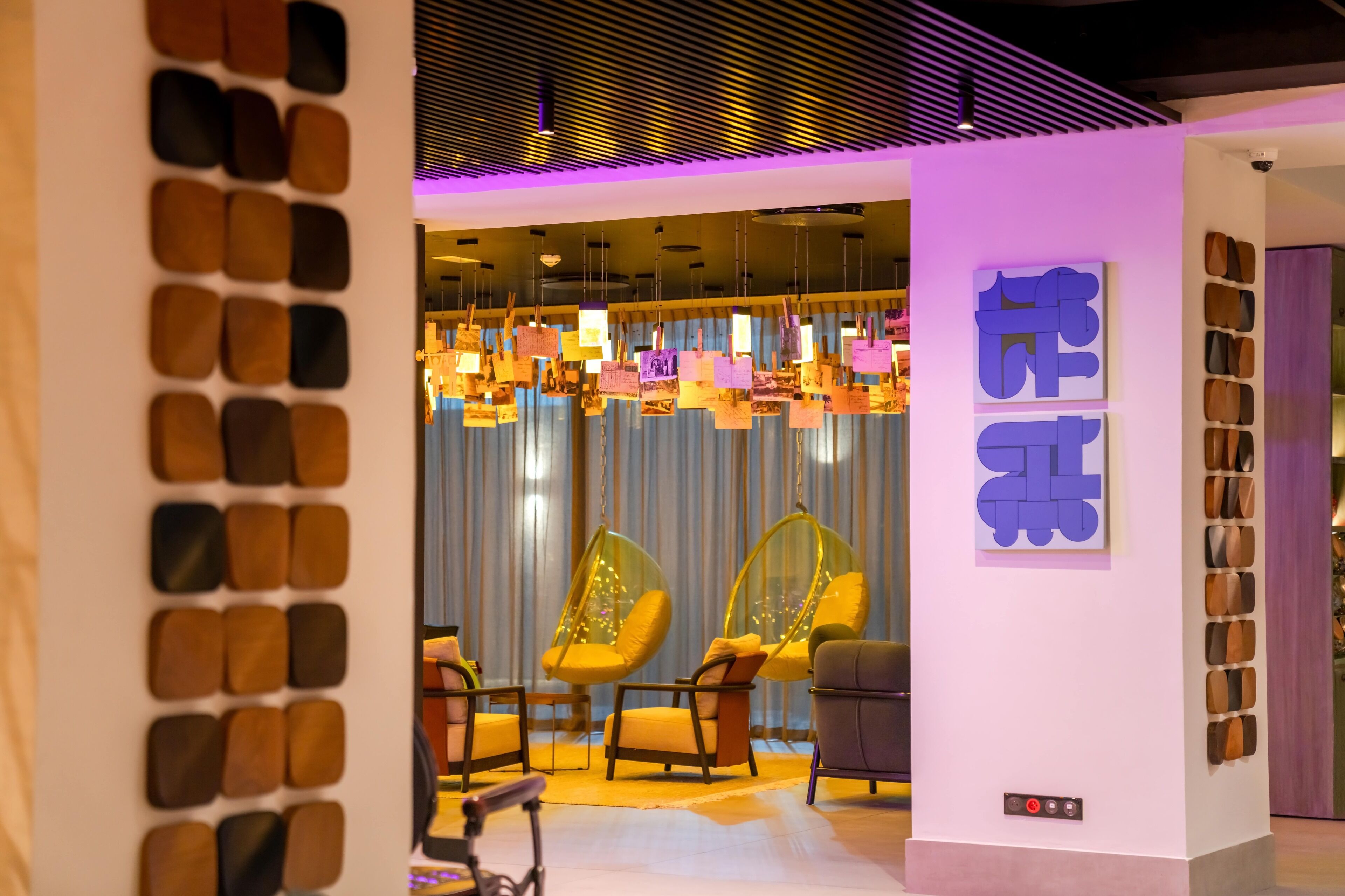 Interior moderno com cadeiras penduradas, uma parede com blocos de madeira e uma placa com caracteres chineses.
