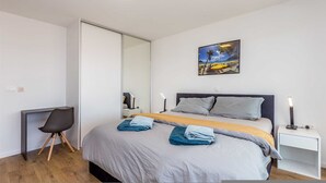 Quarto moderno com cama, mesas de cabeceira, escrivaninha e uma cadeira.