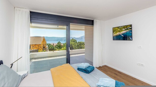Quarto de hotel com uma cama, vista para uma varanda e um quadro na parede.