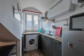 Uma cozinha compacta com máquina de lavar, pia e geladeira.