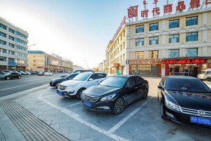Um estacionamento com vários carros, um edifício com placas e um céu claro.