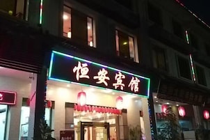Hotel com letreiro neon, entrada visível e lanternas vermelhas tradicionais.