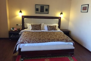 Uma cama bem arrumada com colcha estampada, duas luminárias de cabeceira e um quadro na parede.