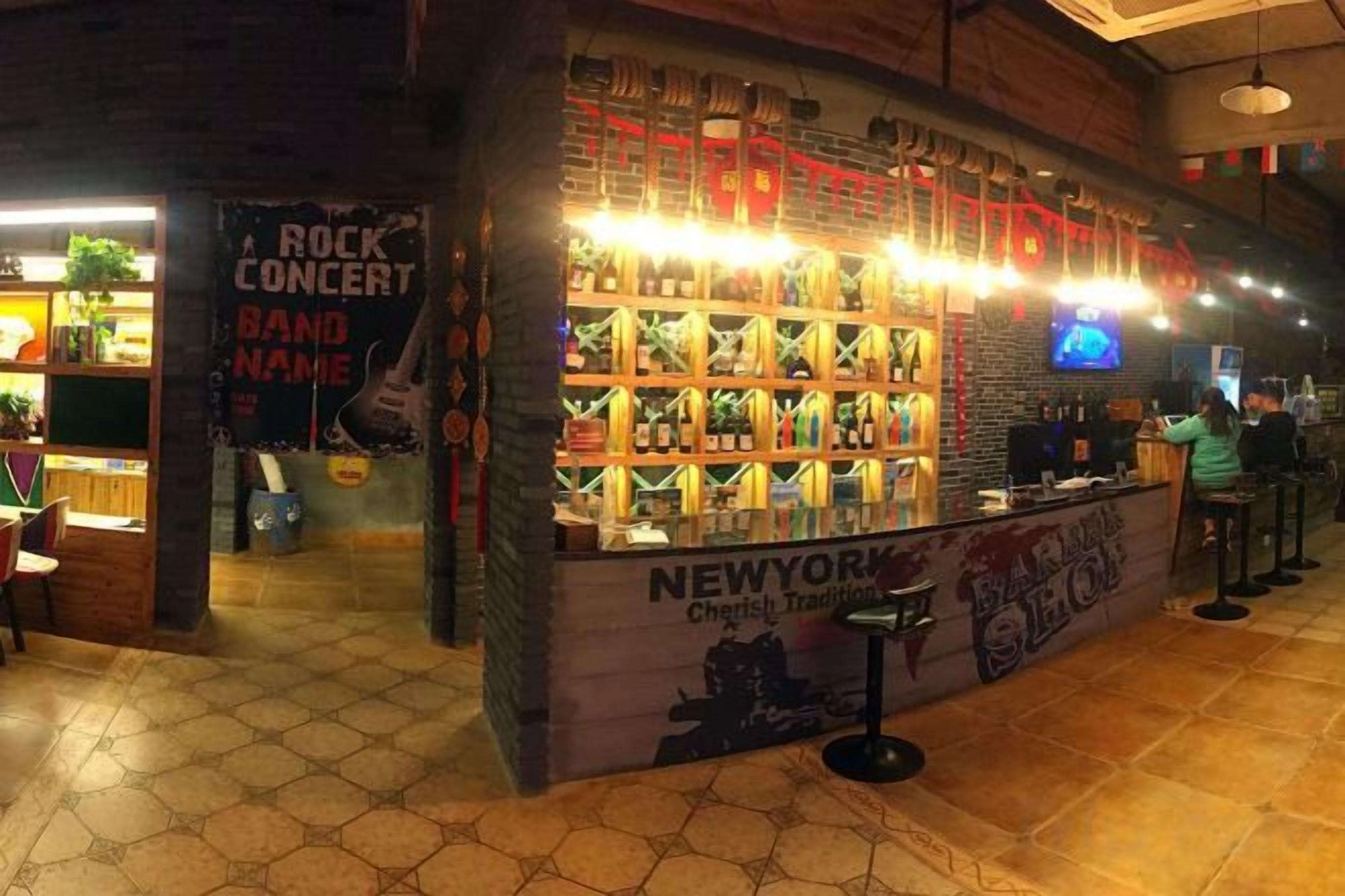 Um bar com tema Nova York, fachada de tijolos, prateleiras cheias de garrafas e balcão.
