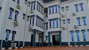 Um edifício com várias andares e fachada simétrica, com diversos janelões e aparelhos de ar condicionado.