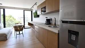 Cozinha moderna com armários de madeira, geladeira de aço inoxidável, micro-ondas embutido e dispensador de água.