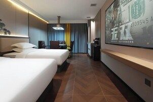 Quarto de hotel com duas camas, uma mesa, uma cadeira e um cartaz grande na parede.