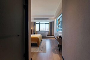 Quarto de hotel moderno com uma cama, uma banheira e uma grande janela com vista para a cidade.