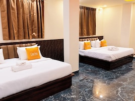 Quarto de hotel com cama, almofadas, cabeceira, cortina e piso de mármore.