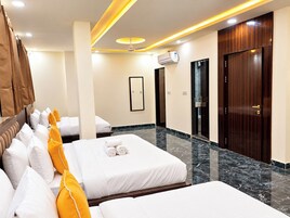 Quarto de hotel com duas camas, ventoinha no teto, ar condicionado e porta de madeira.