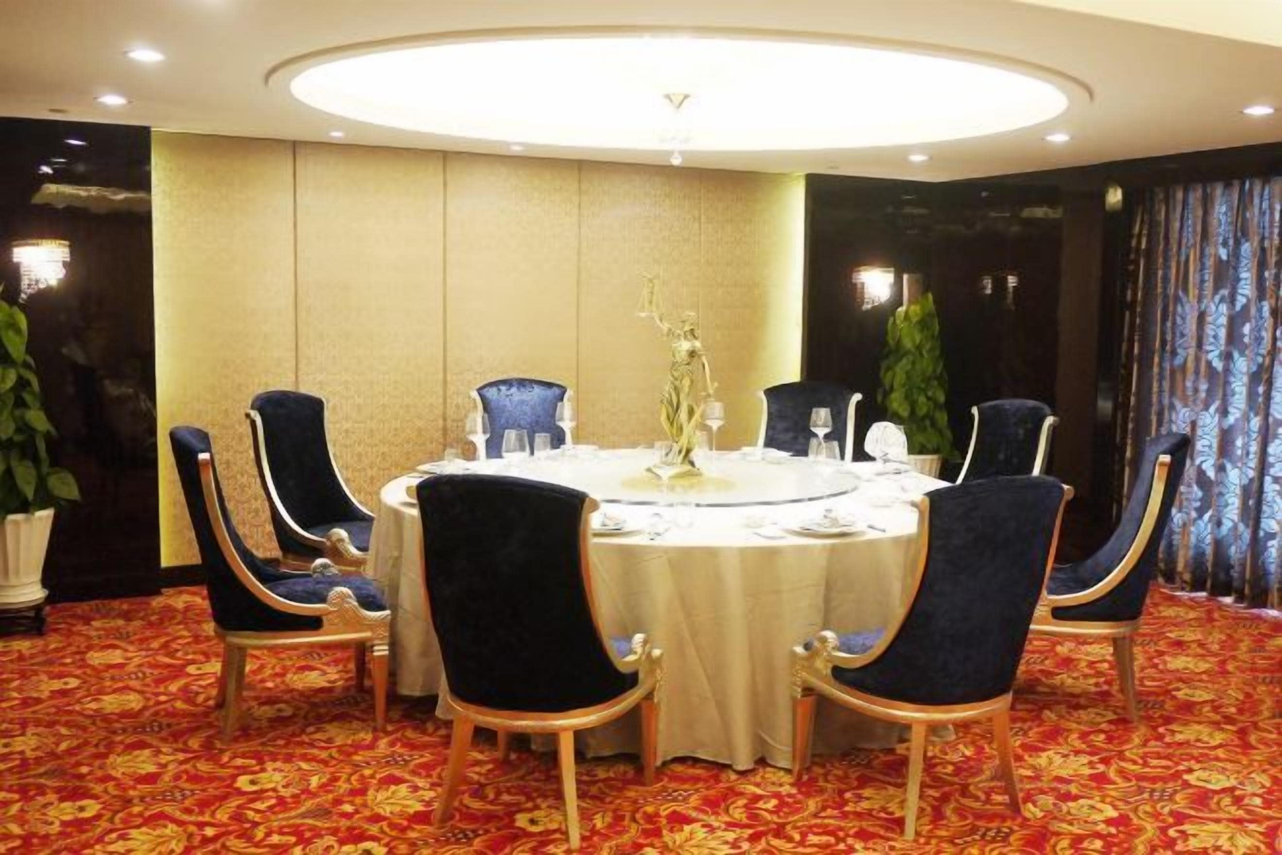 Uma sala de conferências com uma mesa redonda, seis cadeiras e um lustre.