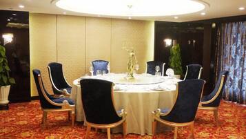 Uma sala de conferências com uma mesa redonda, seis cadeiras e um lustre.