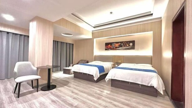 Quarto de hotel moderno com duas camas, uma mesinha e uma cadeira.