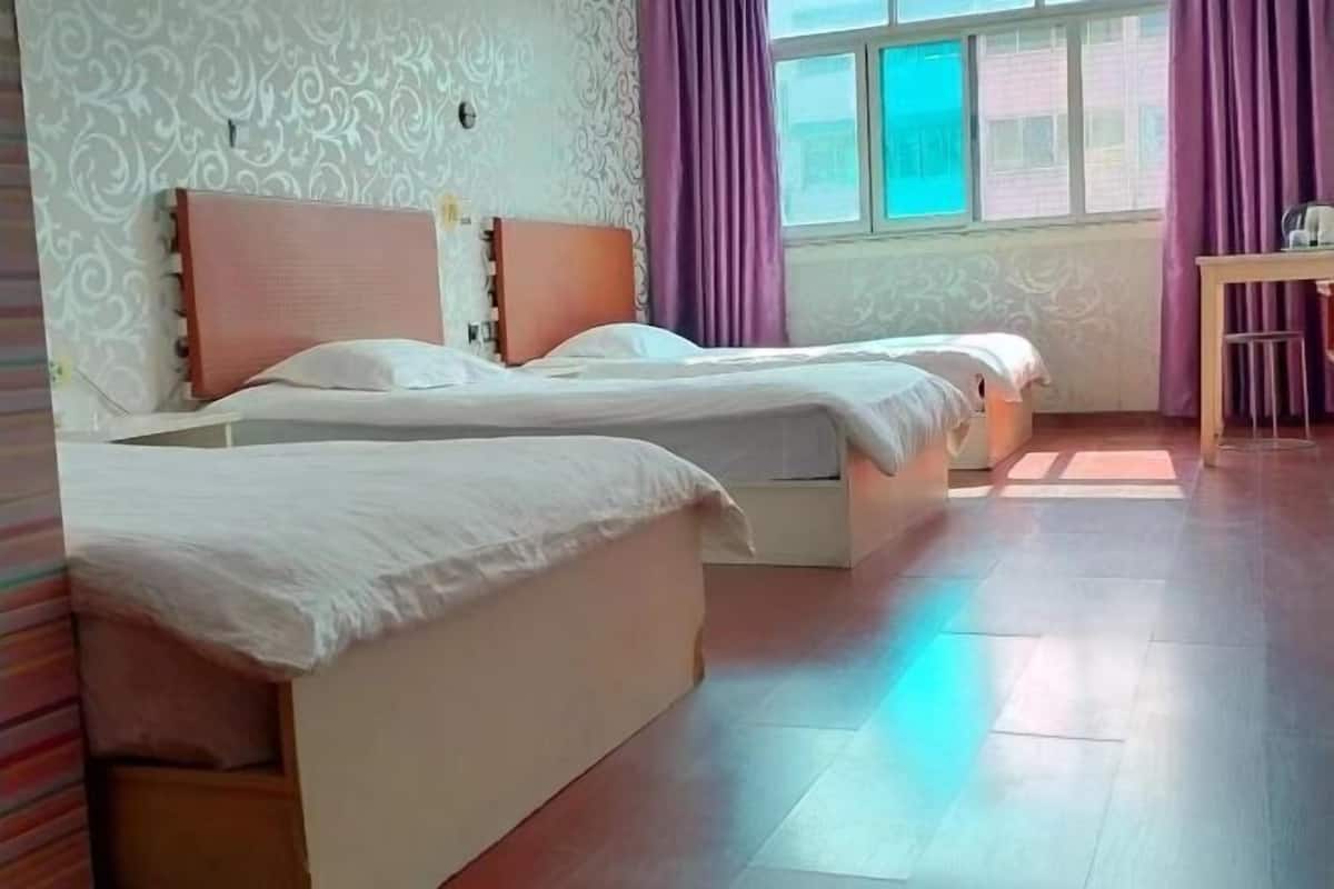 Quarto com duas camas, uma escrivaninha e uma janela com cortinas.