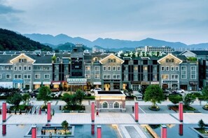 Hotel com um pátio central, vários andares e montanhas ao fundo.