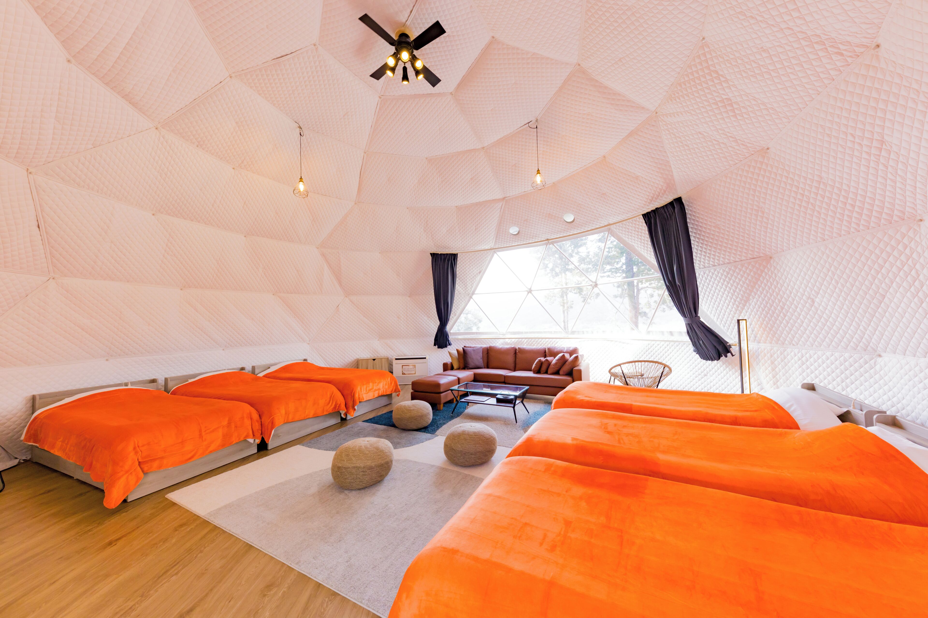 Um espaço amplo e bem iluminado, como uma tenda, com várias camas, um sofá e uma mesa de jantar.
