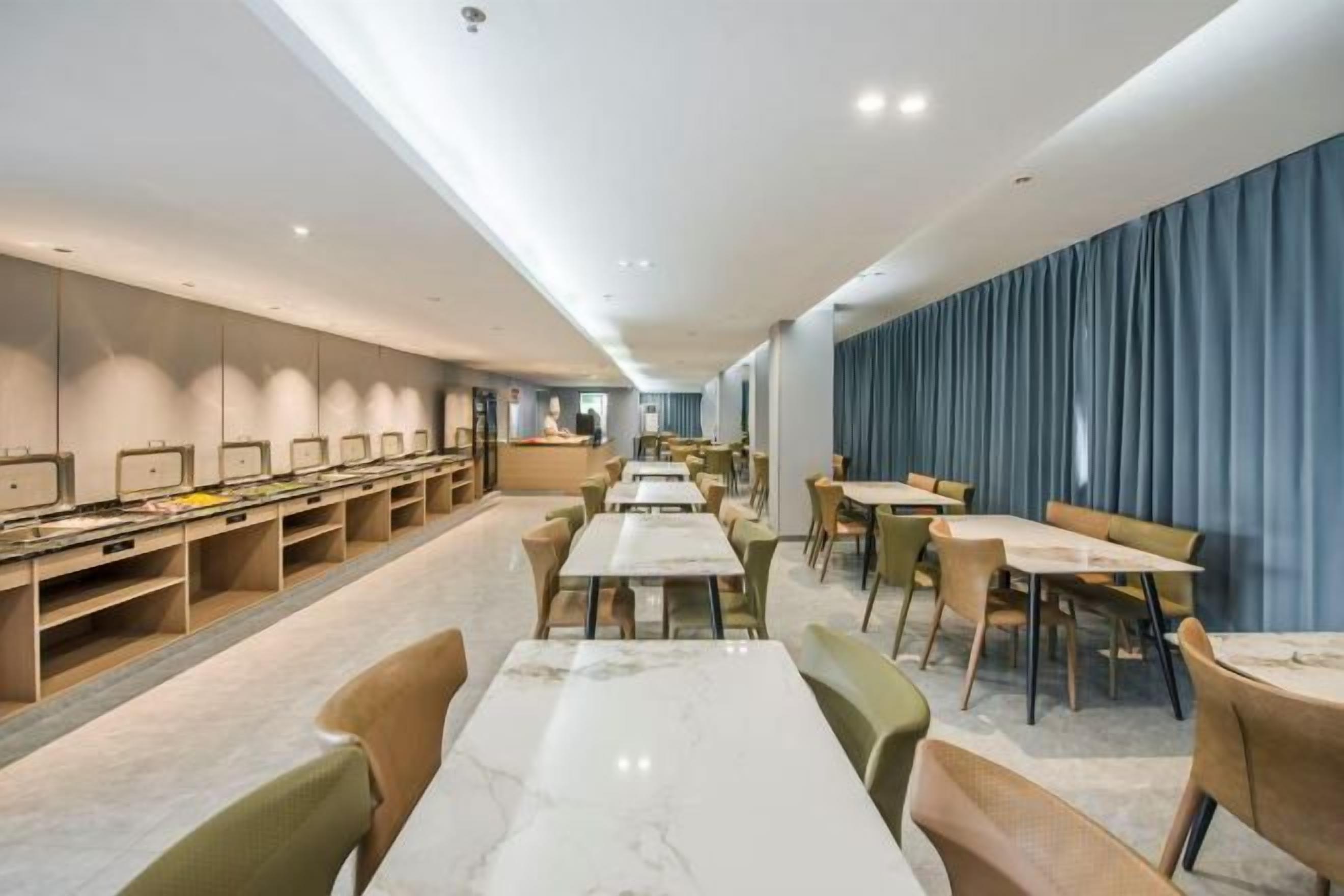 Uma sala de jantar moderna com várias mesas e cadeiras, um balcão e um fundo de cortina azul.