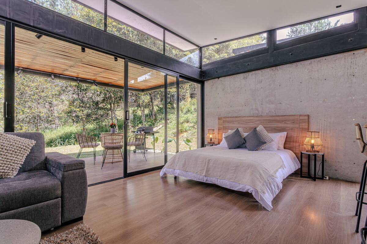 Um quarto moderno com uma cama grande, um sofá e uma mesa de jantar.