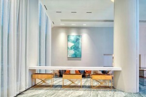 Uma sala de conferências com uma mesa comprida, quatro cadeiras e um quadro abstrato grande na parede.