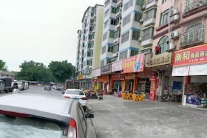 Rua com lojas e um carro estacionado.