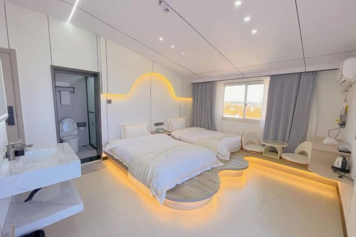 Quarto de hotel moderno com cama, mesas de cabeceira, banheiro e vista para a cidade.