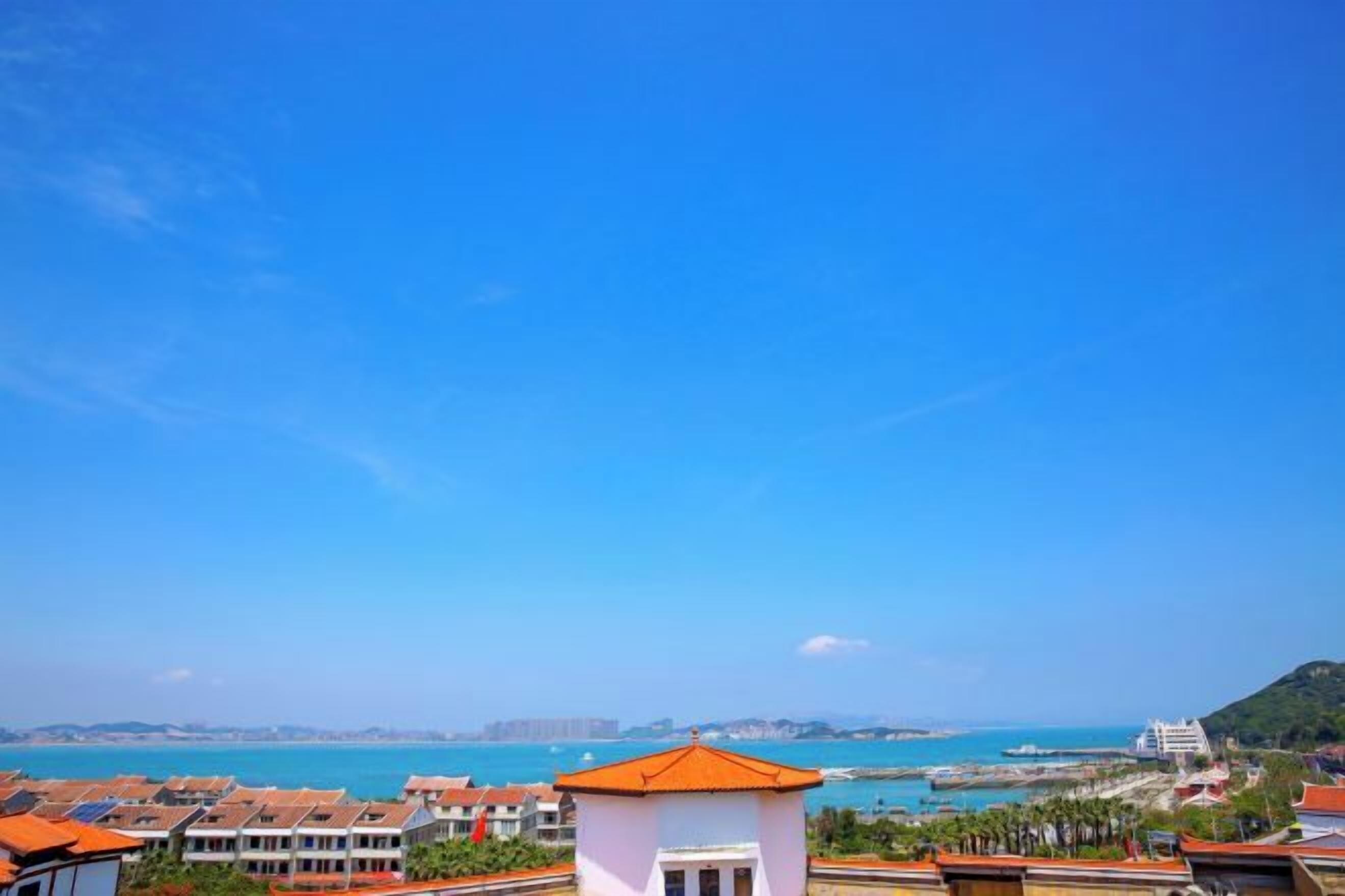 Uma cidade costeira com edifícios, céu claro e vista para o mar.