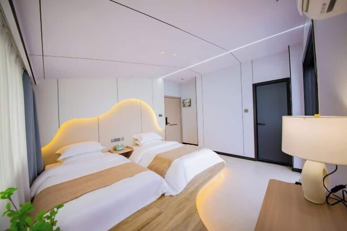 Quarto de hotel moderno com uma cama grande, mesas de cabeceira, uma escrivaninha e uma luminária.