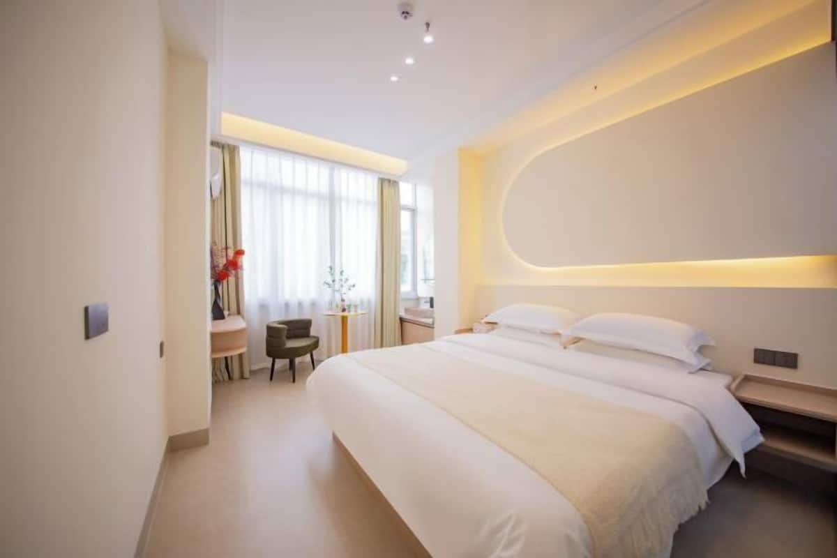 Quarto de hotel moderno com uma cama grande, mesas de cabeceira, uma escrivaninha e uma cadeira.
