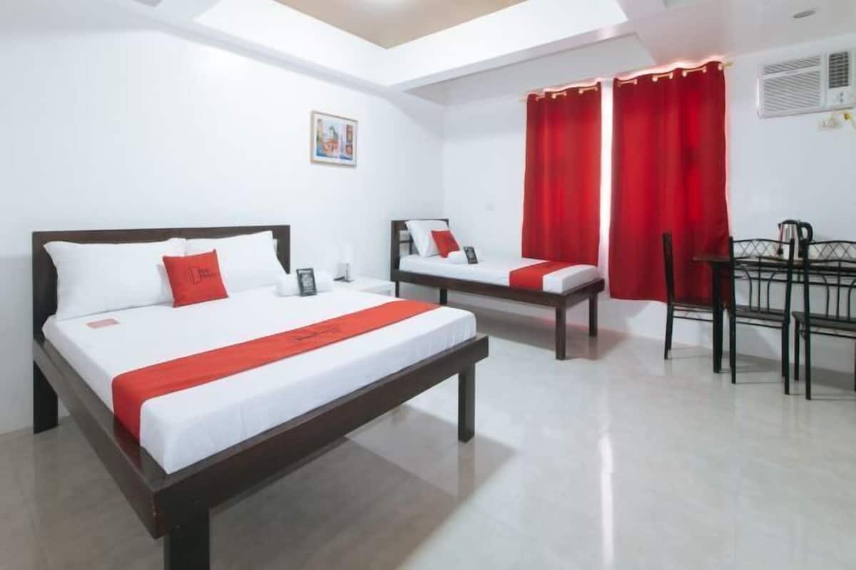 Quarto de hotel com uma cama, uma escrivaninha e uma cadeira.