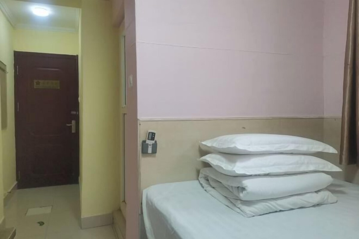 Quarto de hotel com cama, almofadas, mesa de cabeceira e porta.