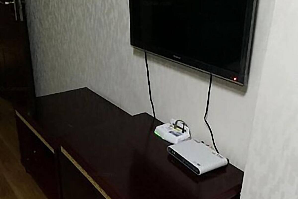 Um móvel de televisão escuro de madeira com uma televisão de tela plana fixada na parede acima.