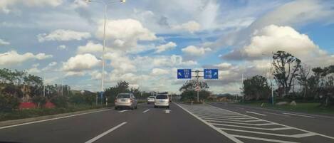 Autoestrada com múltiplas faixas, veículos, placas de sinalização e céu claro.