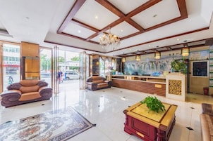 Um hall de hotel com balcão de recepção, área de estar e uma grande janela.