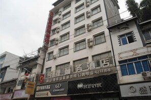 Um edifício de vários andares com vários estabelecimentos comerciais no andar térreo, incluindo uma placa visível para um centro de servi ços empresariais.