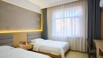 Quarto de hotel com duas camas, uma escrivaninha e uma cadeira.