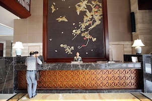 Bancada de recepção com um grande mural decorativo, design em painel de madeira e duas luminárias.
