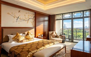 Quarto de hotel com cama grande, sofá, escrivaninha e varanda vista para a cidade.