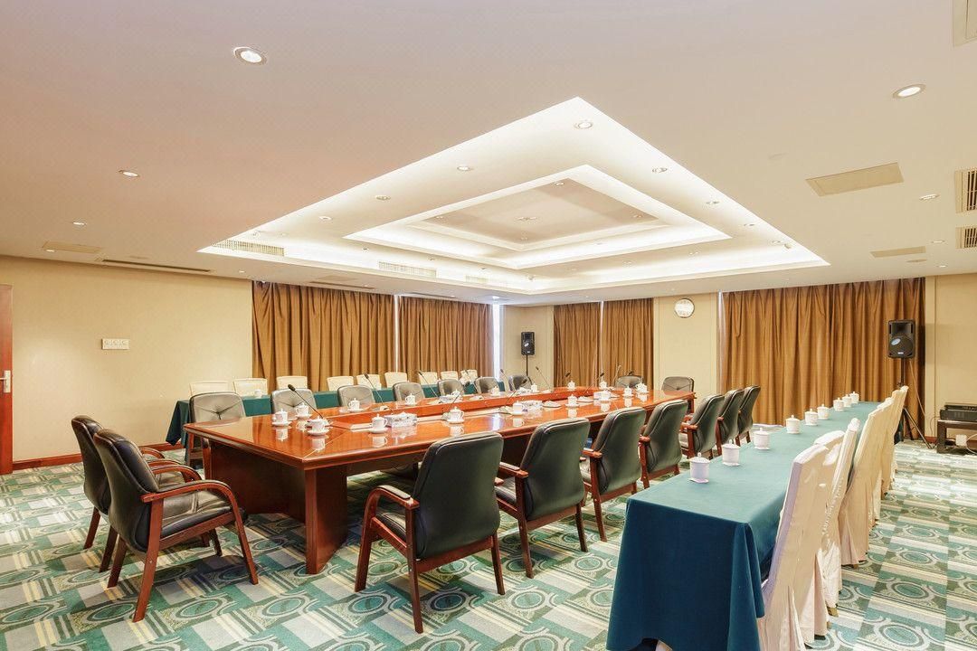Uma sala de conferência com uma mesa comprida, cadeiras e um palestrante.