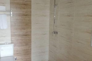 Casa de banho com chuveiro, suporte para toalhas e sanita.