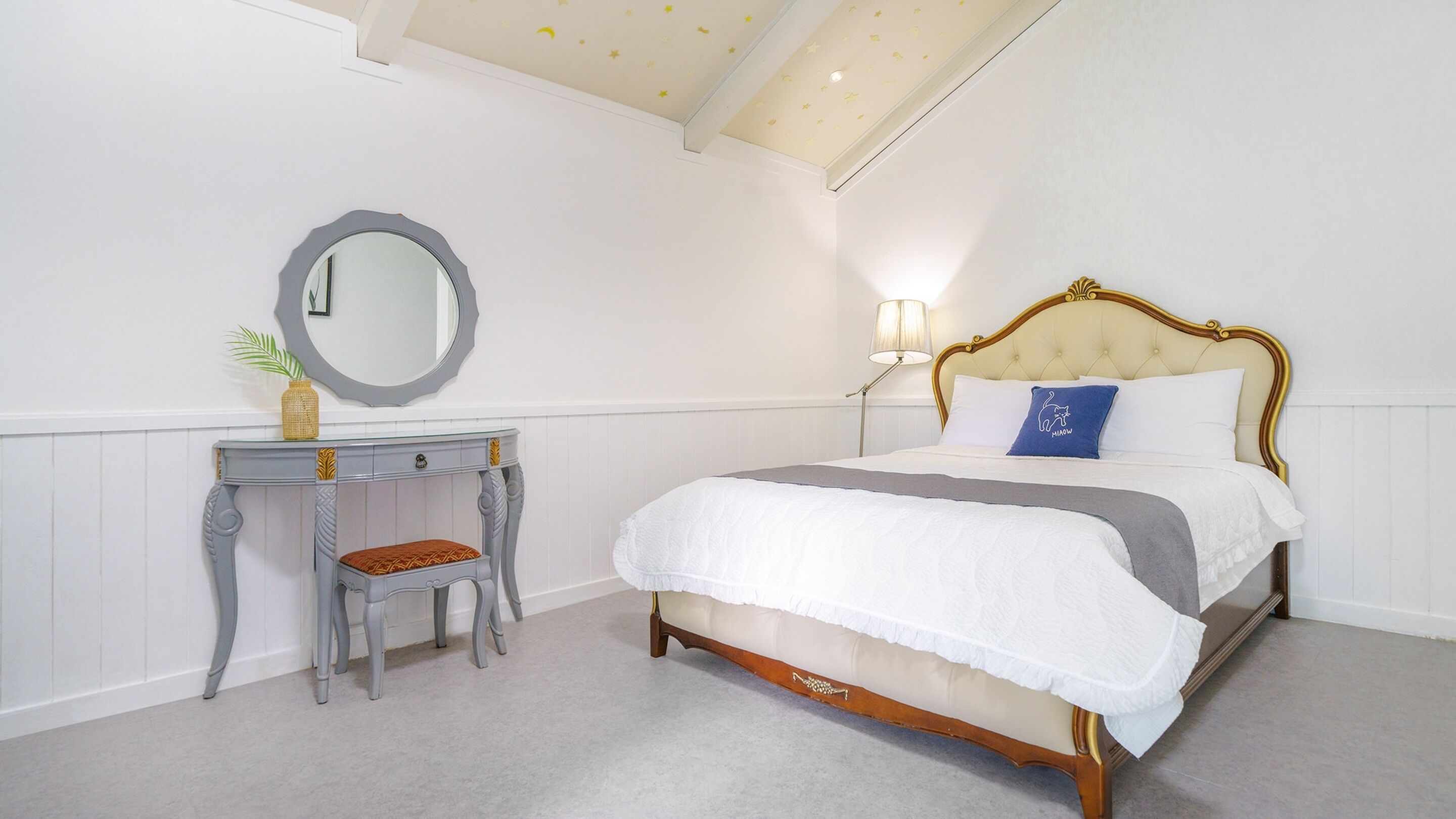 Quarto com uma cama, mesa de cabeceira com espelho, cadeira e abajur.