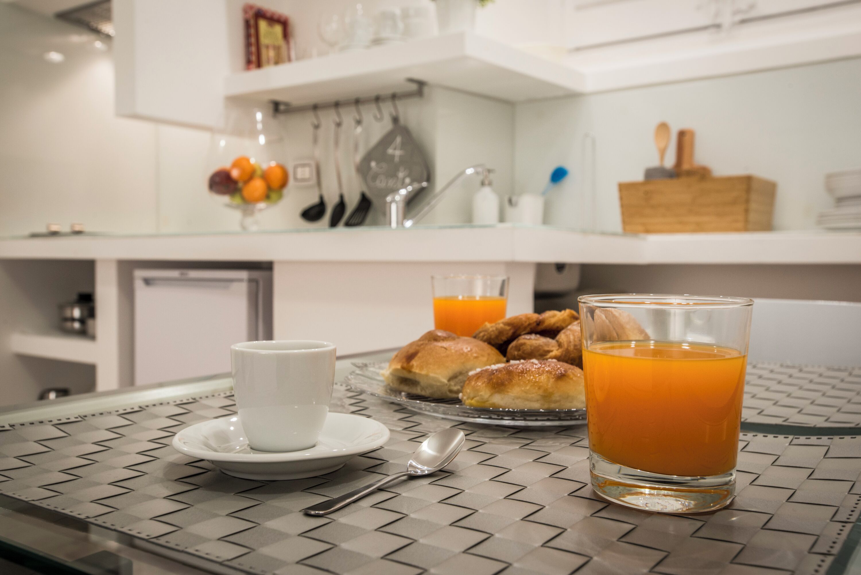 Mesa posta para o café da manhã com uma xícara, um copo de suco de laranja e pães.