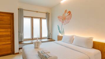 Quarto de hotel com uma cama grande, janela com cortinas, cabeceira de madeira e pintura floral na parede.