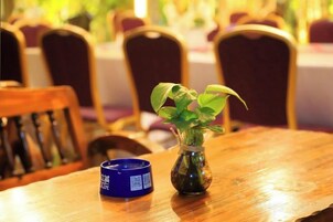 Uma mesa de madeira com um pequeno vaso de plantas verdes e um objeto azul.