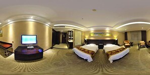 Quarto de hotel com duas camas, televisão, escrivaninha e  área de estar.